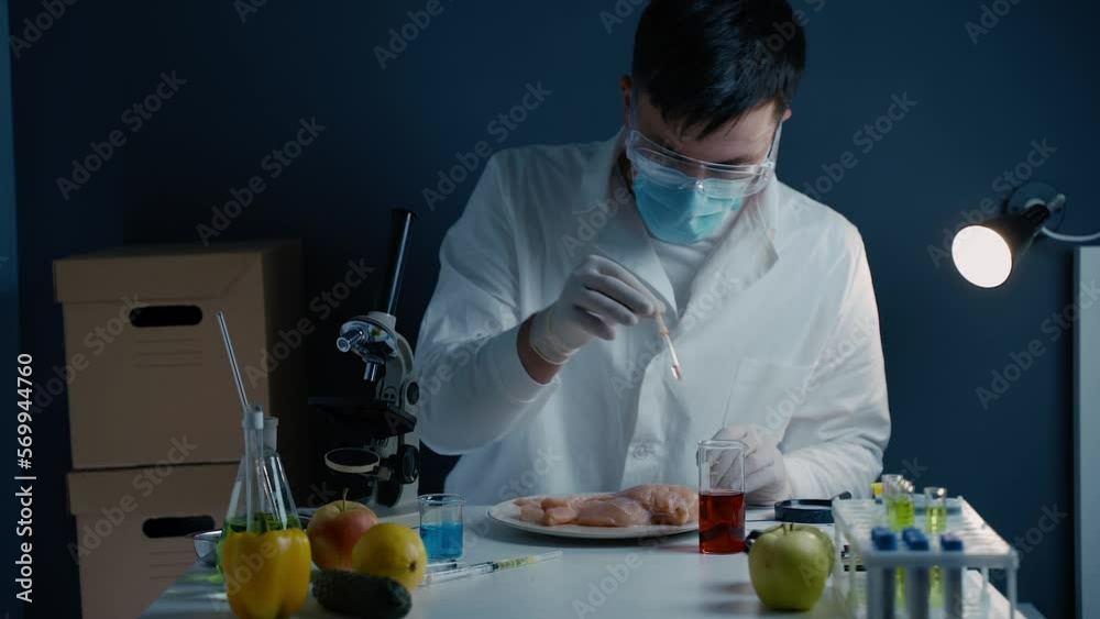 Genetics laboratory technician takes red liquid from a glass vial with ...