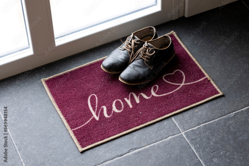 An indoor portrait of two stylish blue shoes standing on a welcome home ...