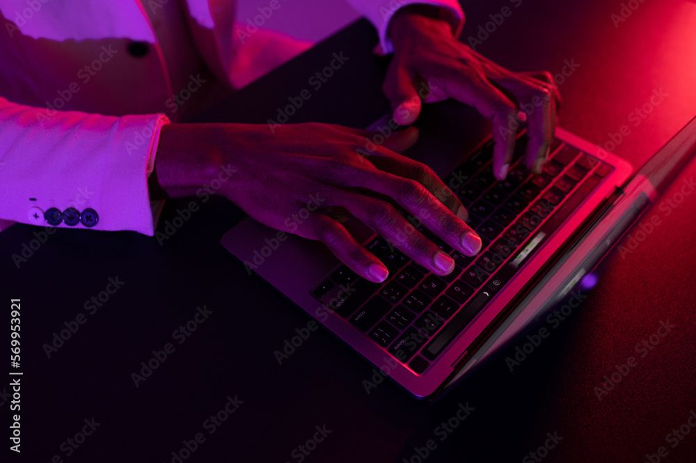 a man types text on the keyboard. working at the computer at night ...