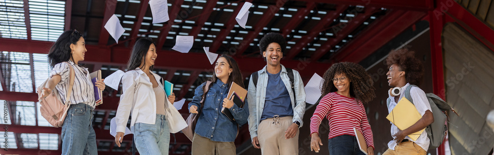 diverse friends and female classmates talking happily while leaving ...