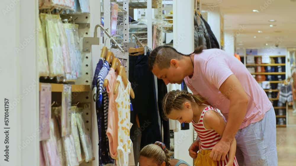 Beautiful family father mother and daughter shopping in clothes shop ...