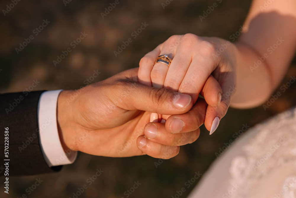 Young married couple holding hands, ceremony wedding day on the sunset ...