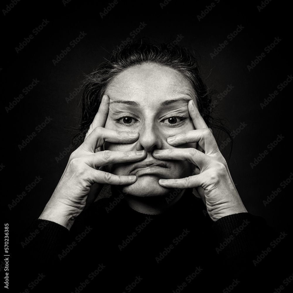 Conceptual dark portrait of old woman stretching the skin of her face ...