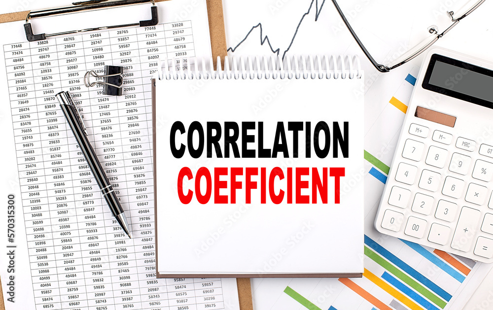 CORRELATION COEFFICIENT text on notebook with chart, calculator and pen ...