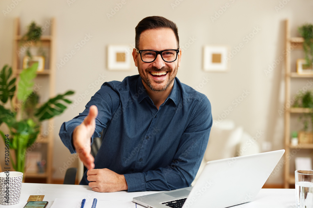 Handsome business man with a smile on his face is sitting at a desk and ...