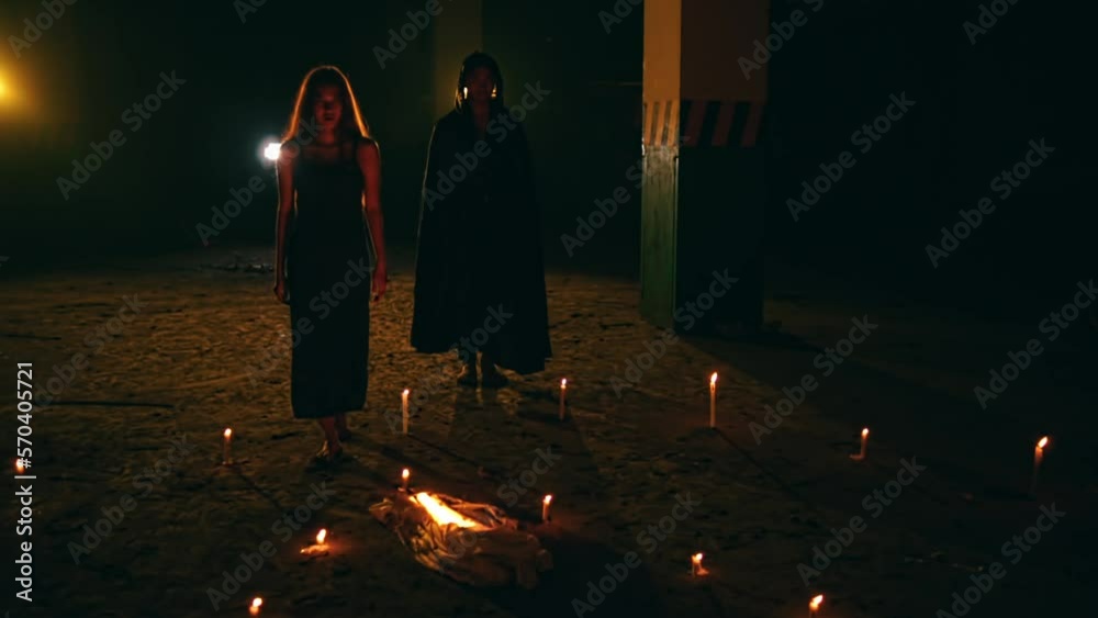 a group of satanic cultists walk amidst an altar of pentagrams and lit ...