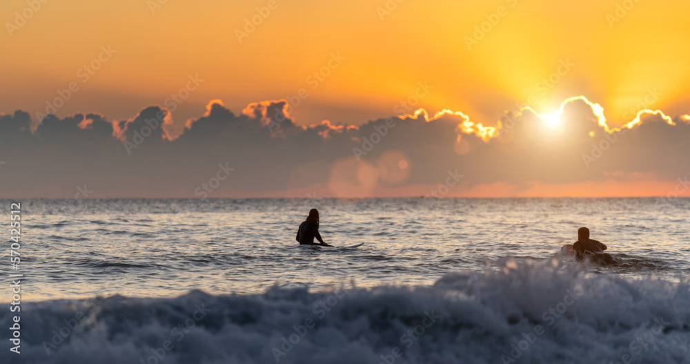 surfer sitting on their surfboard in the blue ocean and waiting for a ...