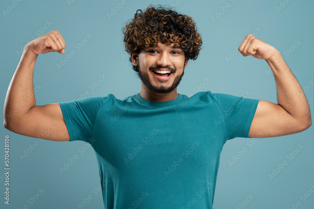 Strong smiling Indian man showing muscles, biceps looking at camera ...