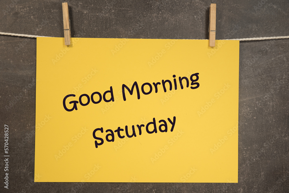 Napis good morning Saturday na wiszącej żółtej kartce, na ciemnym tle ...