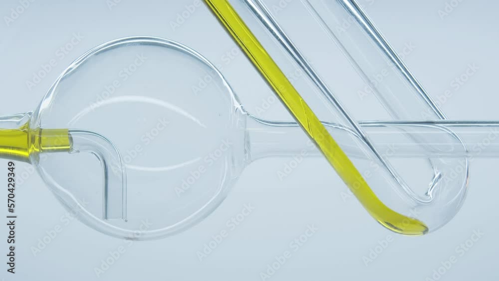 Video Stock Yellow natural oil flows through laboratory spherical glass ...