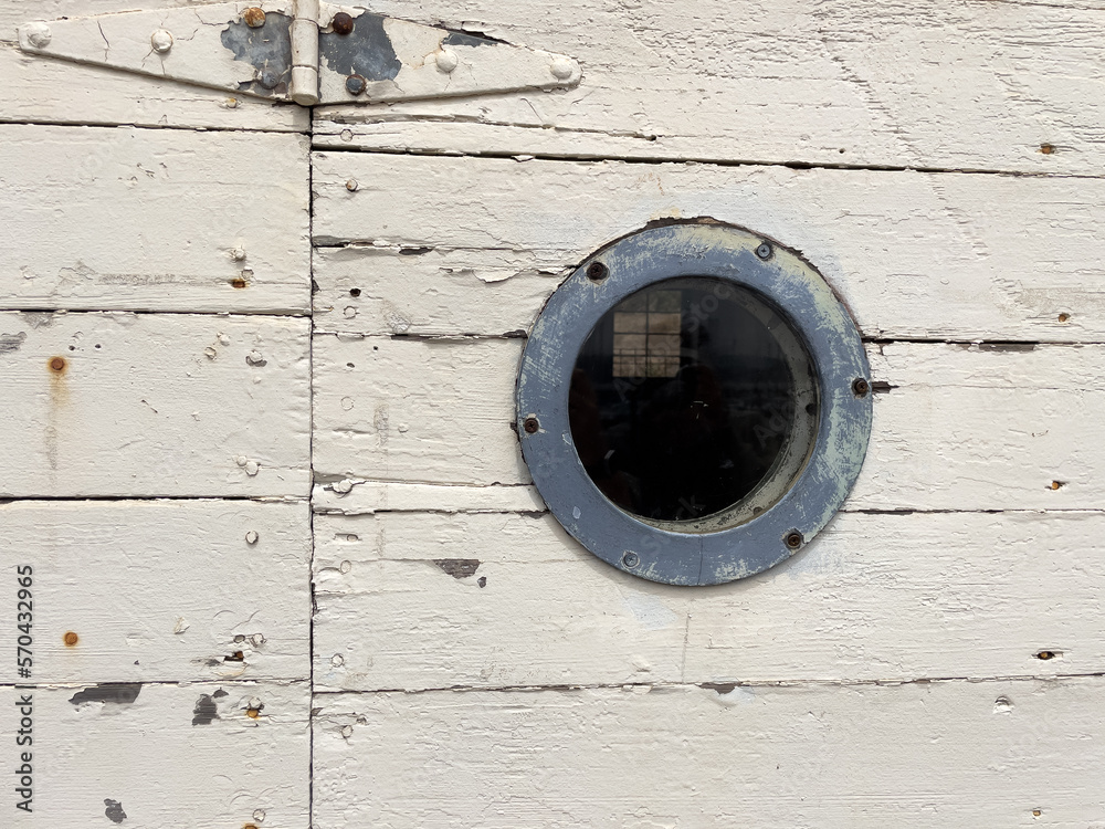 metal and glass port hole window in hinged white, rough wood door at ...