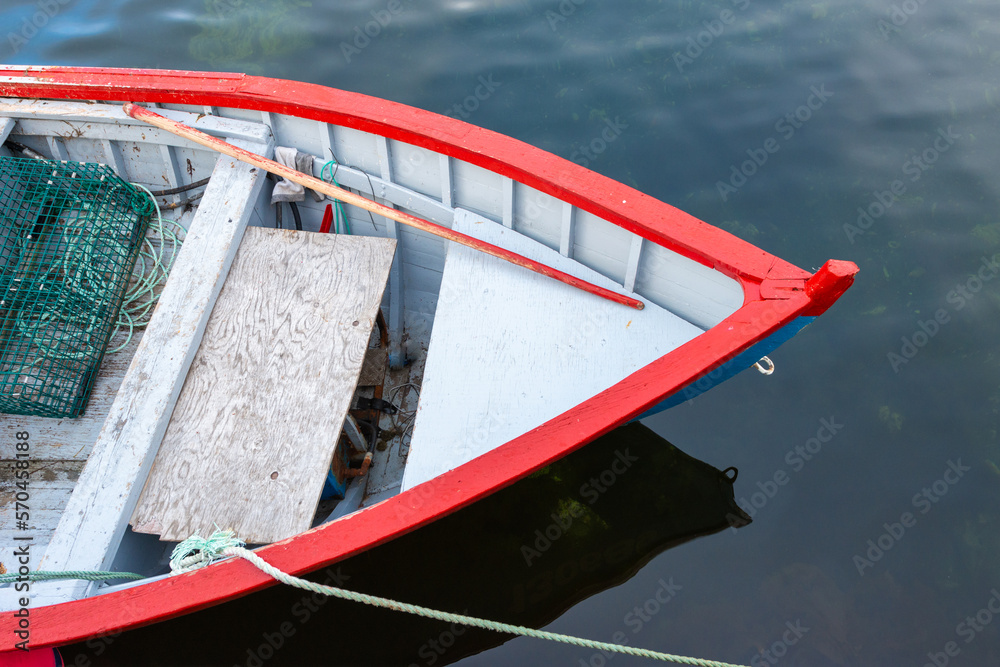 A white wooden traditional dory or small fishing vessel with red trim ...