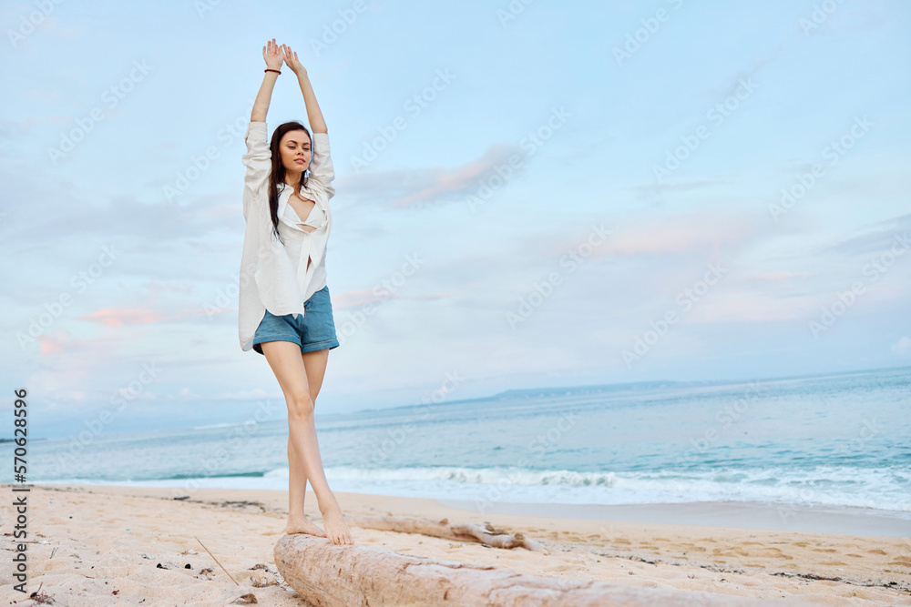 Happy tanned woman in white swimsuit shirt and denim shorts walks on ...