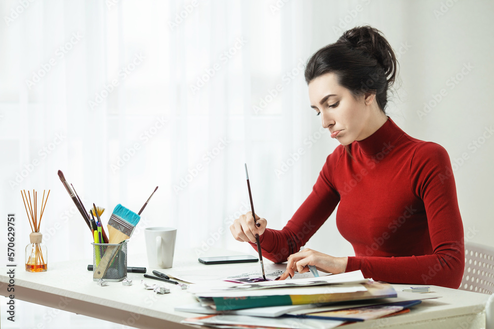Girl draws on canvas in a bright office. Artist`s model. Woman painter ...