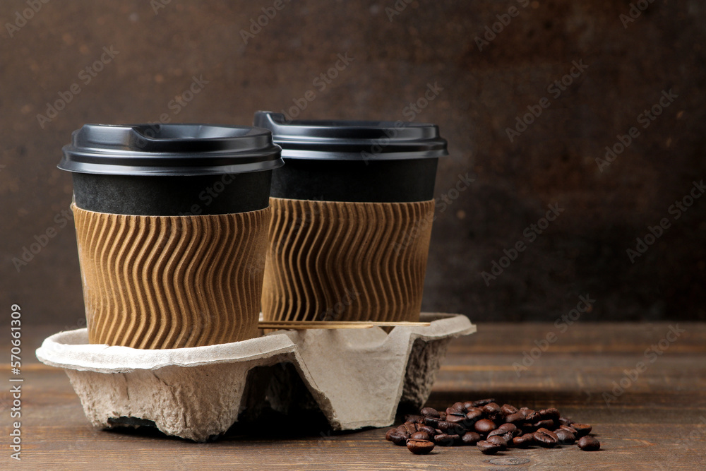 Paper cups with coffee on a stand and coffee beans on a brown table ...