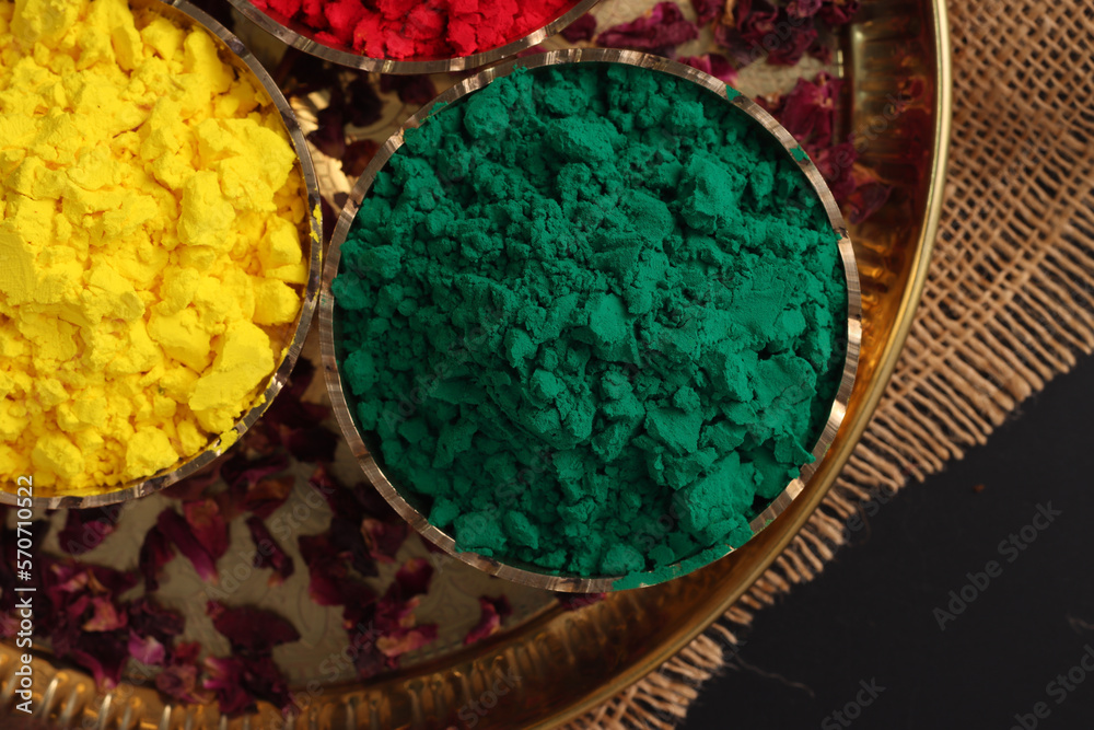 Colorful organic dry powder abeer gulal in traditional brass bowl with ...