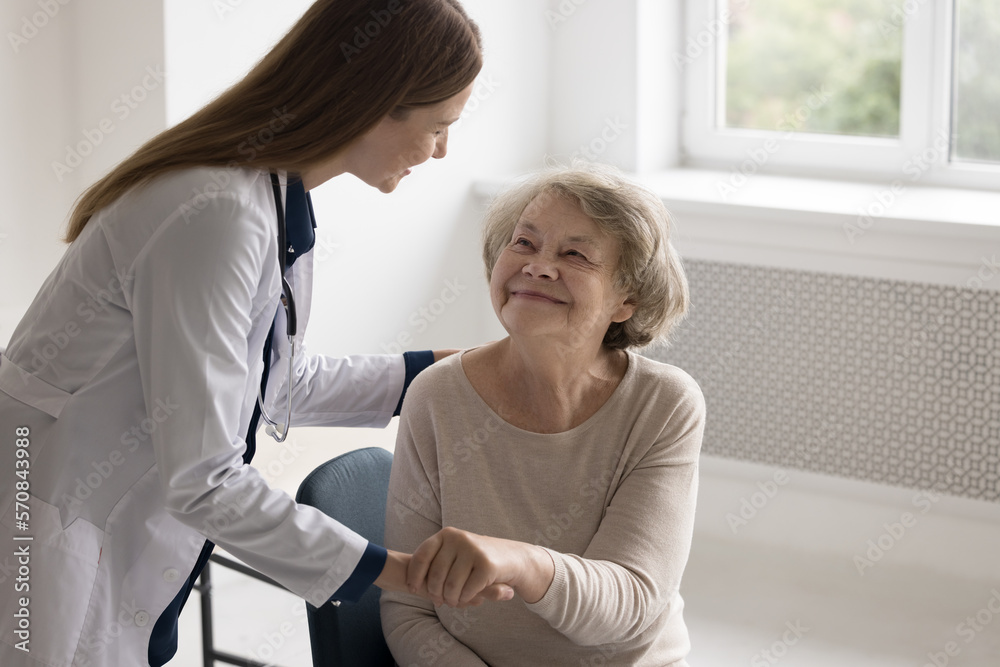 Positive empathetic doctor woman giving comfort to elderly patient with ...