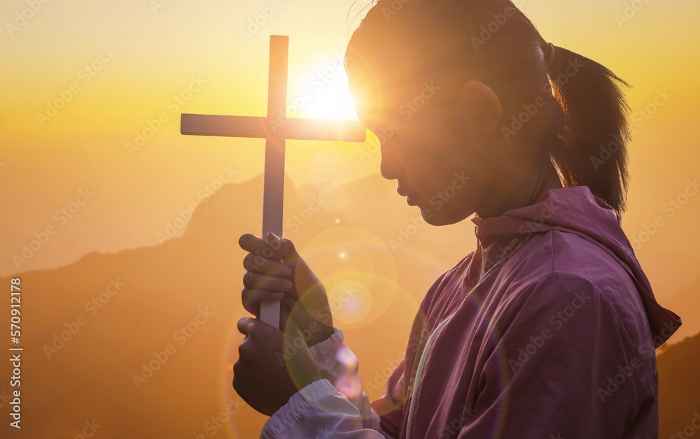 Christian child girl praying with a cross at sunset sky background ...