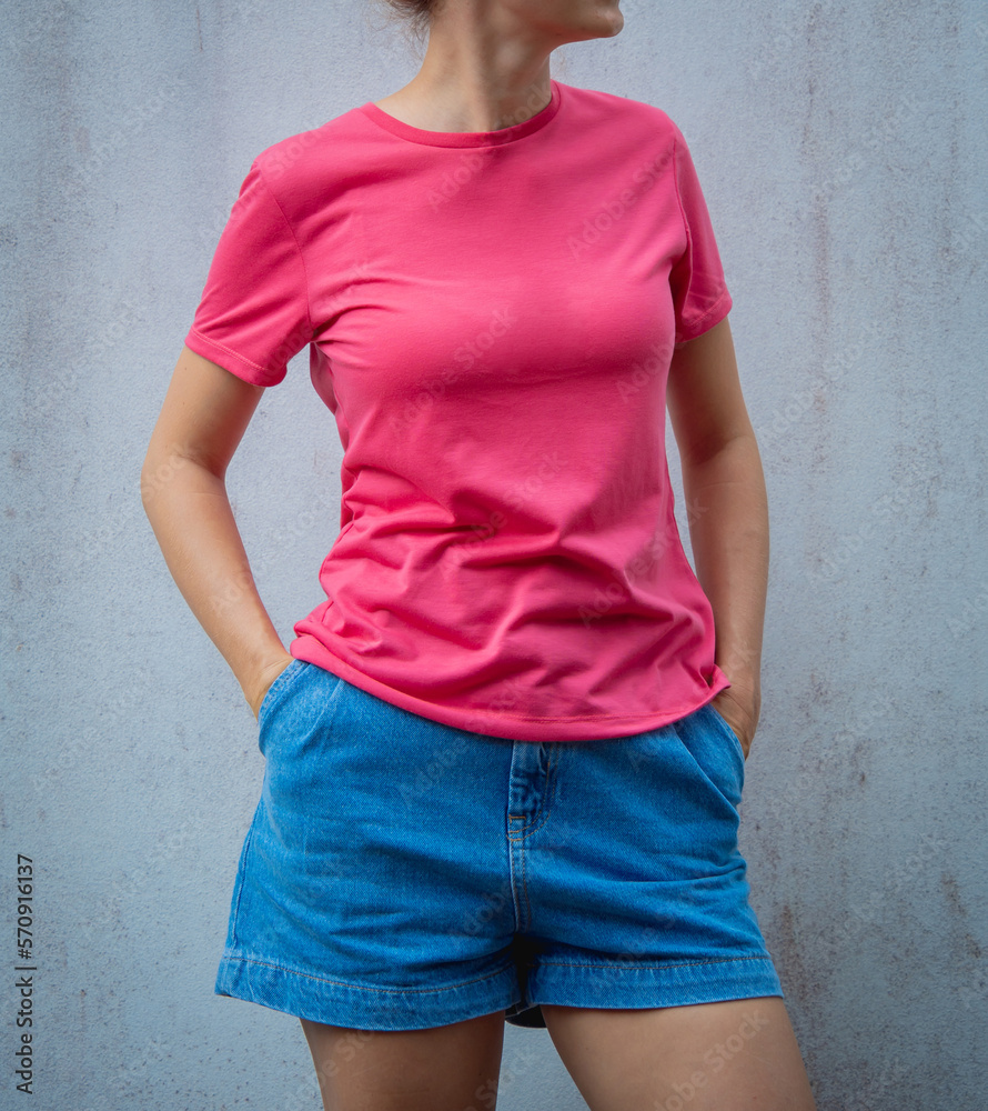 Female model wearing pink blank t-shirt on the background of an gray ...