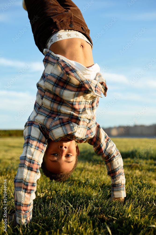 Outdoor image of black male kid of 13 standing in upside down position ...