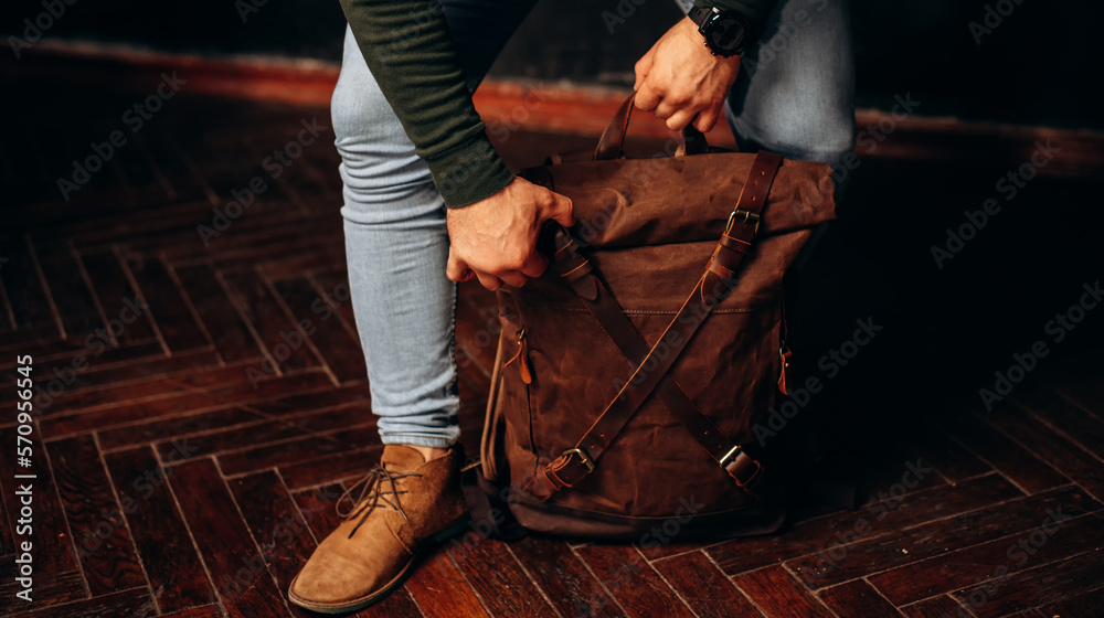 man's hand holding a canvas backpack. Model wears a brown belt bag ...