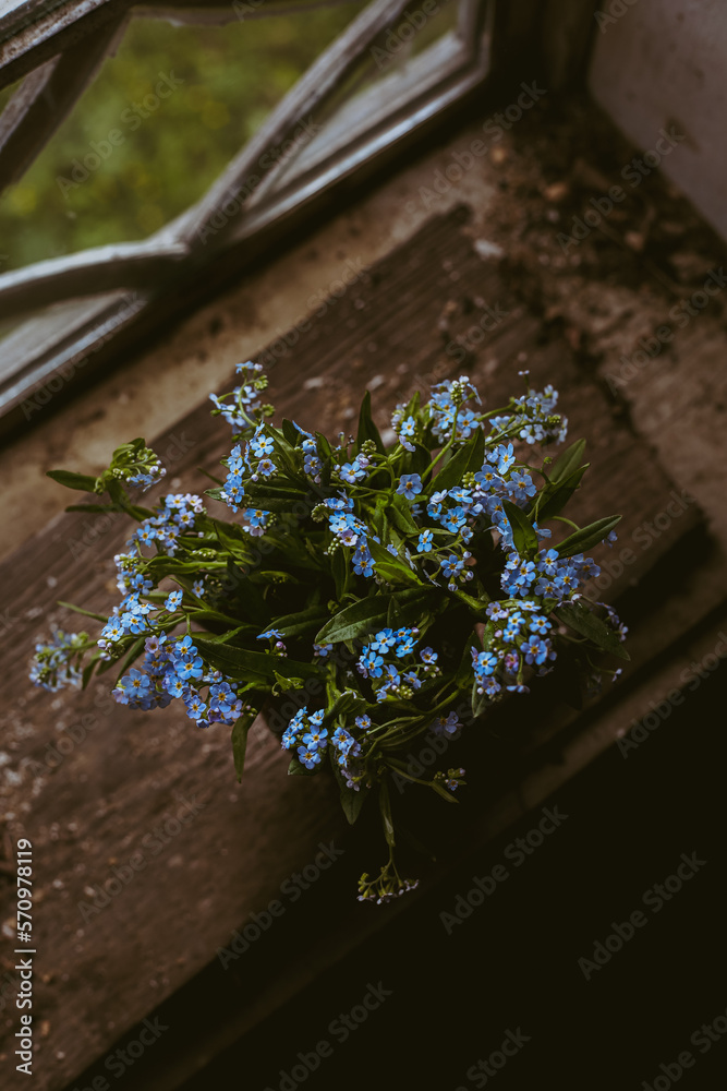 Bouquet of wild flowers of blue forget-me-nots in a vase on a wooden ...