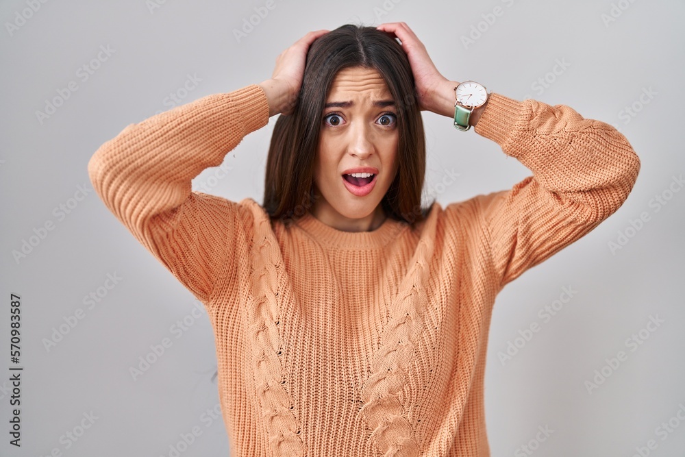 Young brunette woman standing over white background crazy and scared ...