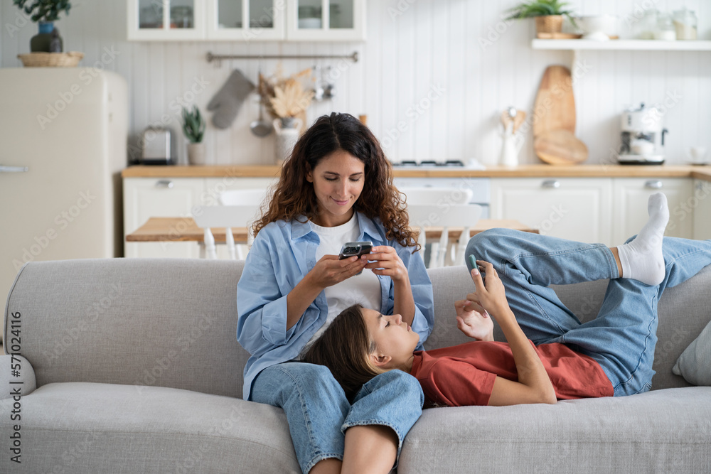 Mother and teenage daughter resting at home with electronic gadgets ...