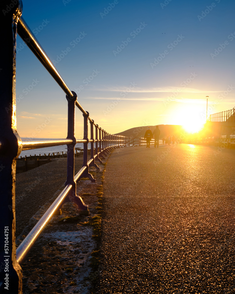 Blue railings on Eastbourne promenade with clear sunset sky. Pebbled ...