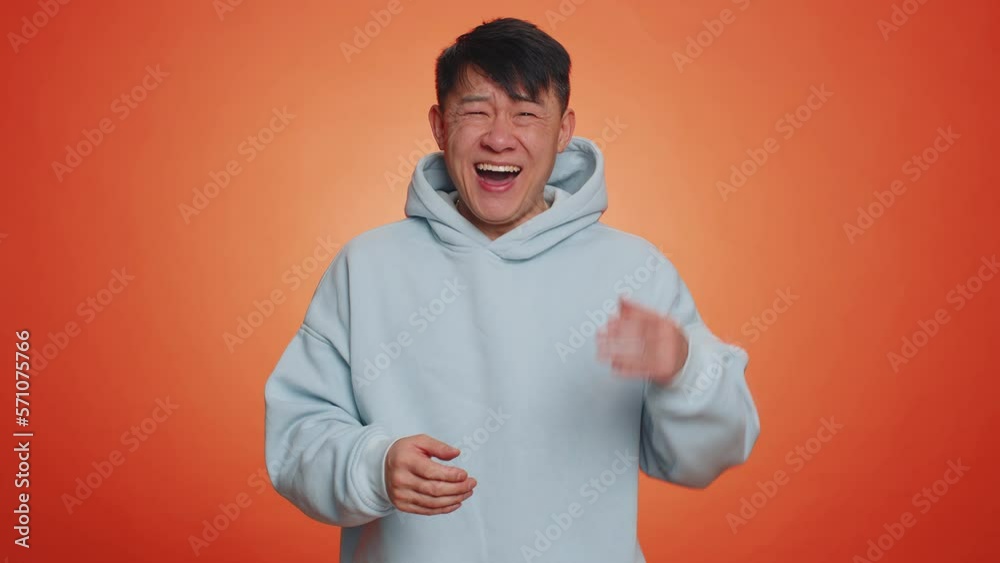 Amused asian man pointing finger to camera, laughing out loud, taunting ...