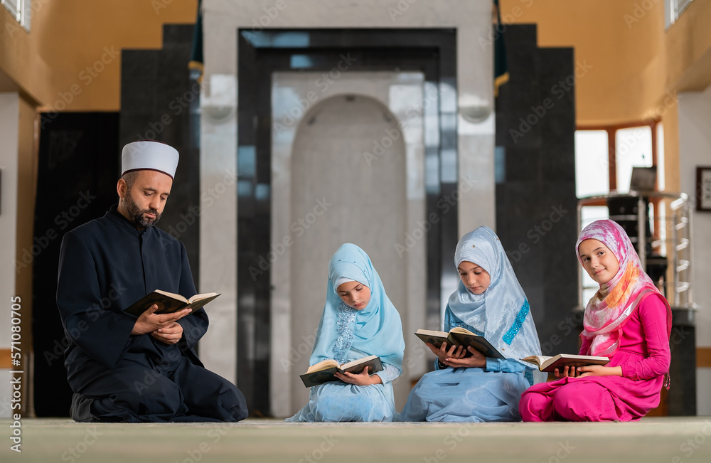 Foto de A Muslim teacher teaches children girls to read a holy book ...