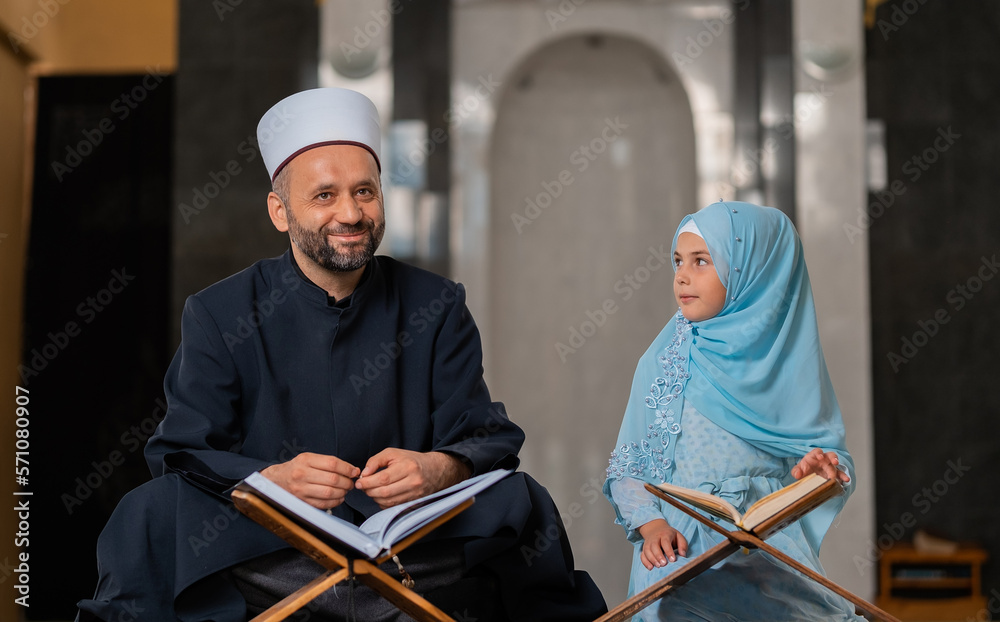 A Muslim teacher teaching child girl to reading a holy book Quran ...