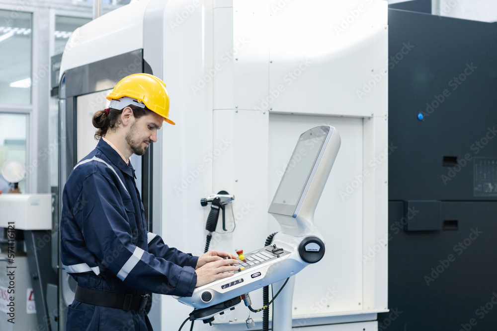 Man engineer using computer controlling cnc machine at workshop ...