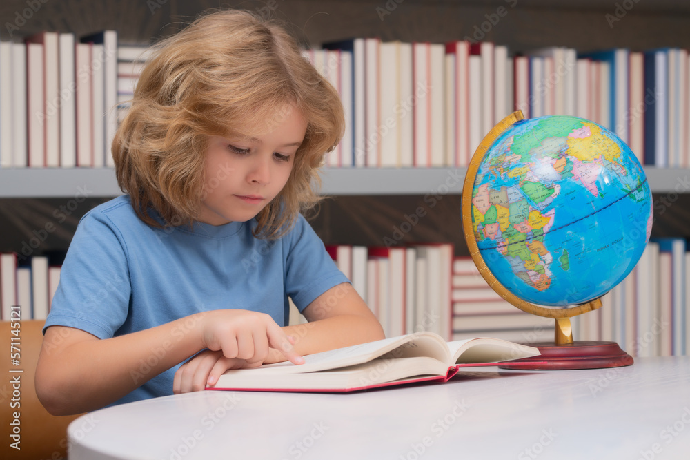 School boy looking at globe in library, geography lesson. School child ...
