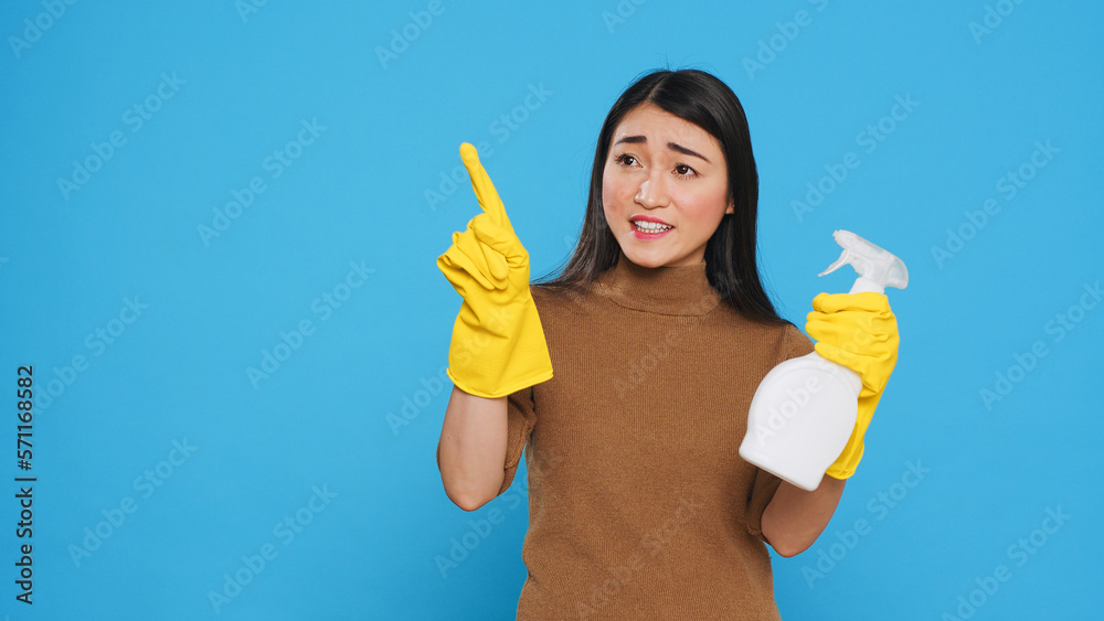 Professional maid pointing and showing cleaning product or isolated ...