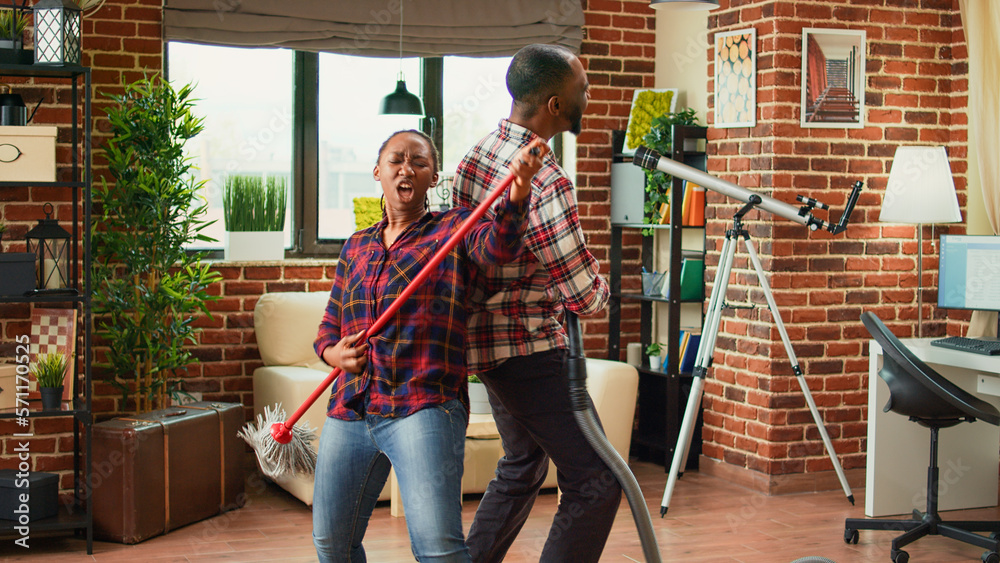 Smiling couple dancing and cleaning apartment with music, showing dance ...