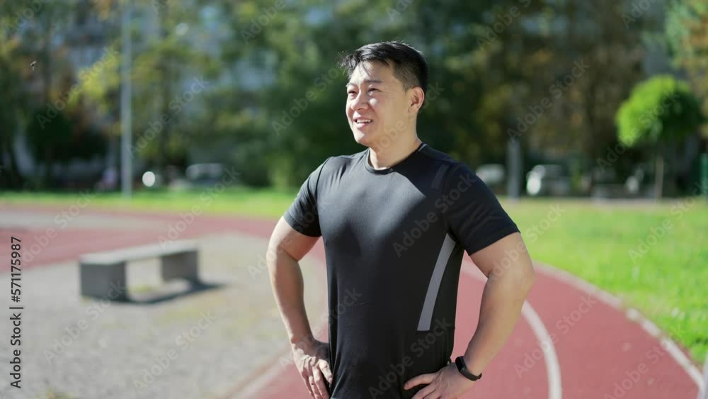 Young adult asian runner relaxes after jogging while standing in urban ...