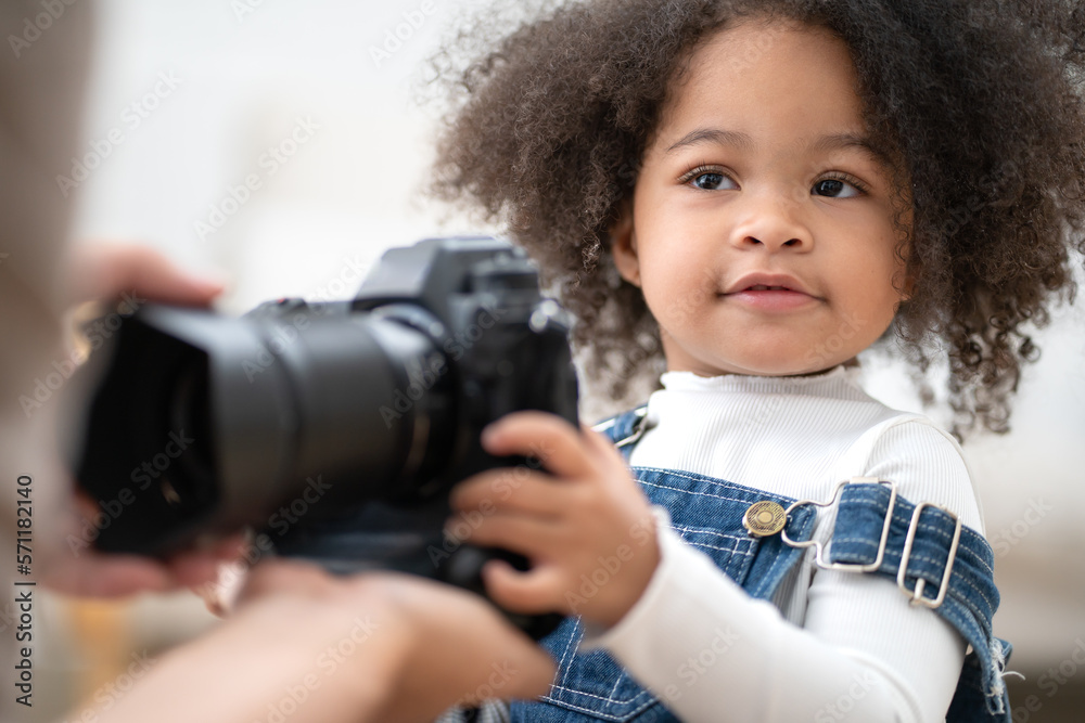 Cute little girl holding camera with smile. Portrait of playful ...