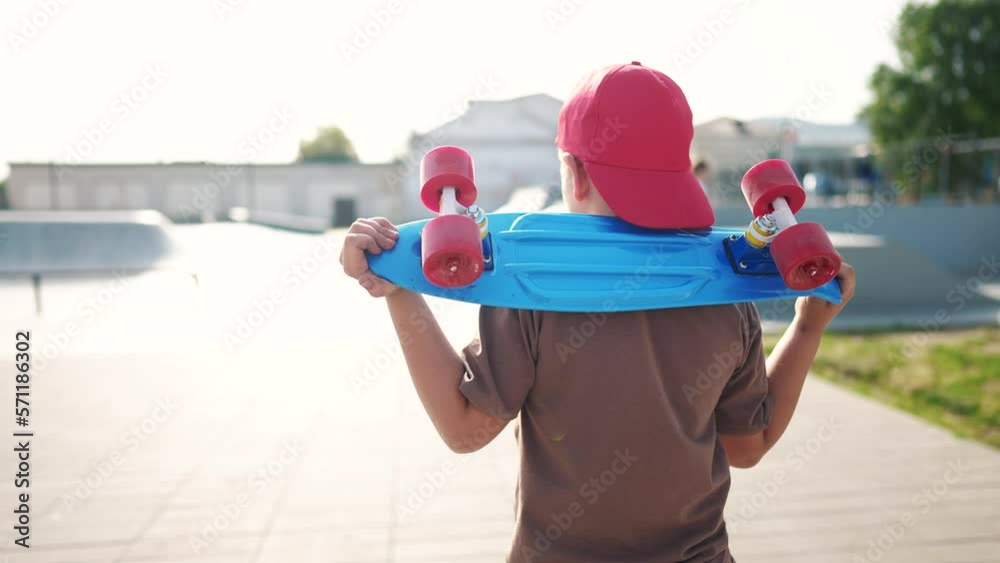 child walk with a skateboard. boy in a red cap with a skateboard on the ...