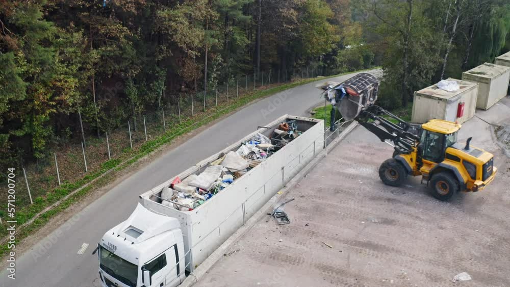Skid steer loader loading a truck with waste material transferred for ...