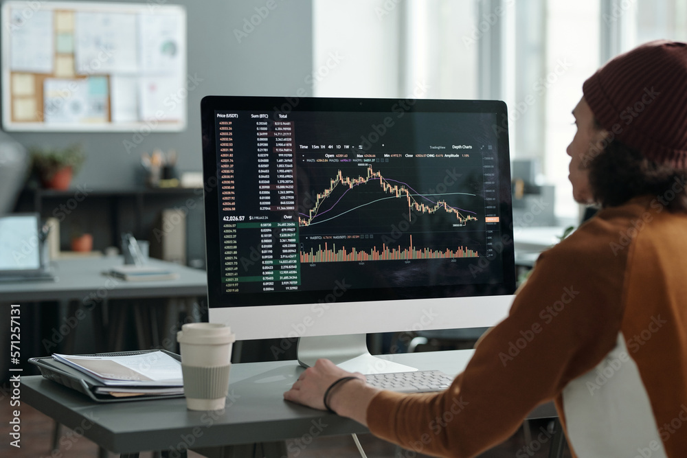Male analyst sitting in front of computer monitor with graph ...