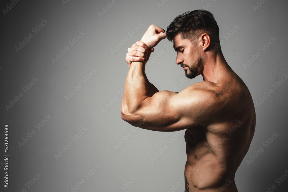 Muscle handsome young man with stylish haircut posing over gray ...