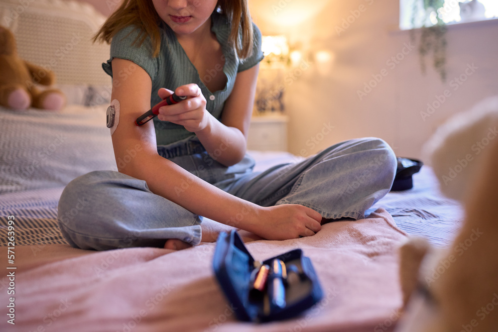 Foto de Close Up Of Young Diabetic Girl Sitting On Bed In Bedroom At ...