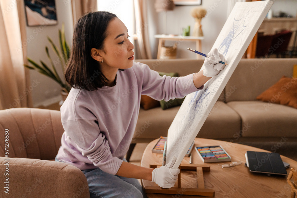 Beautiful asian girl artist drawing with pencil on canvas while sitting ...