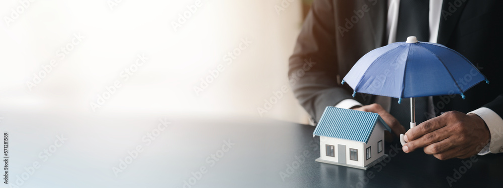 Individuals holding small umbrellas and model homes, housing insurance ...