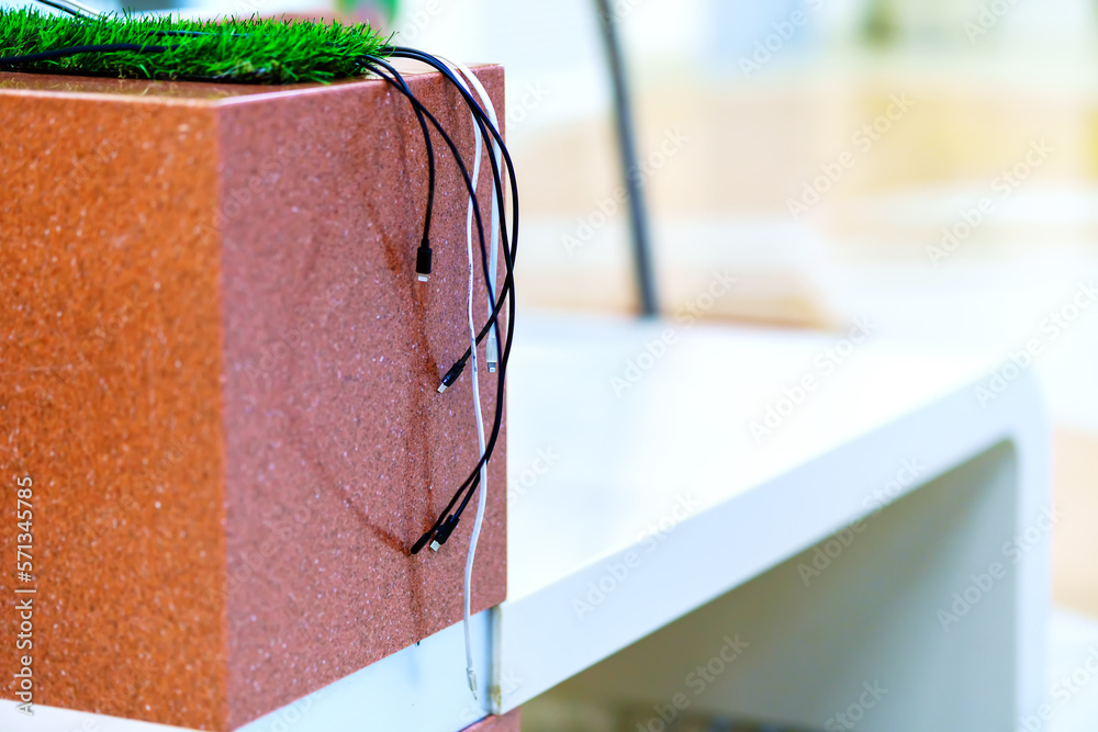 Various wires for charging electronic gadgets on a bench in a shopping ...