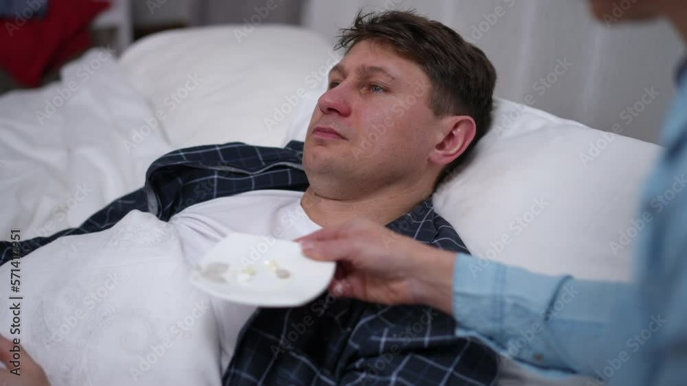 Desperate depressed ill man lying in bed as unrecognizable woman ...