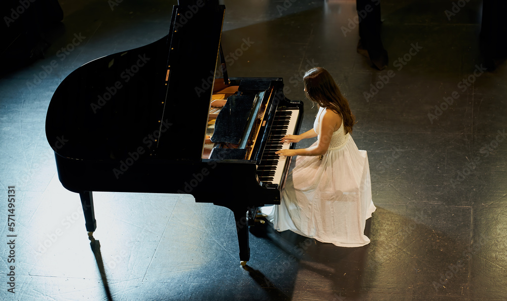 A woman with brown hair dressed in a white dress seen playing a black ...