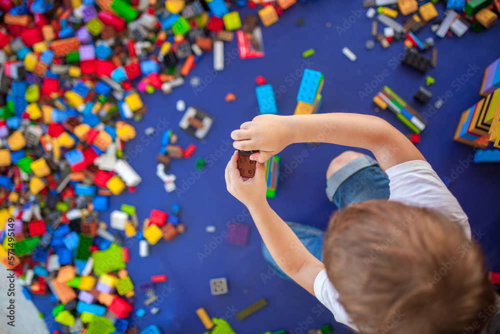 4 years boy building a tower with with interlocking plastic bricks ...