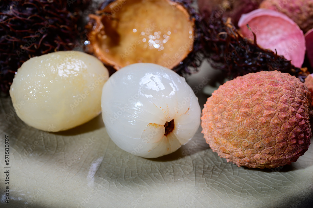 Tasty tropical exotic fruits, ripe fresh peeled and unpeeled lychee and ...